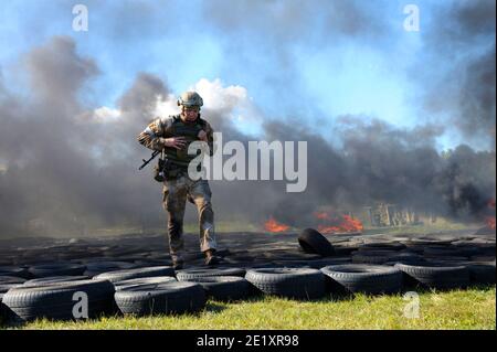 Fully equipped soldier running through tires during obstacle course ...