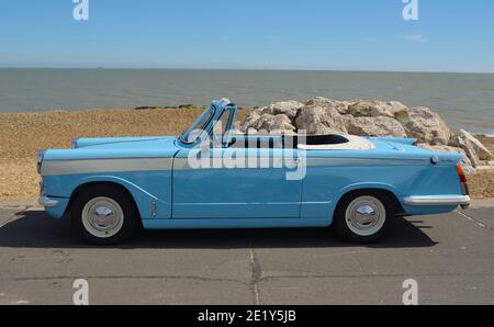 Classic light Blue Triumph Herald open top motor car parked on seafront ...