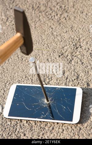 A hammer smashing the screen of a handheld electronic device, isolated ...