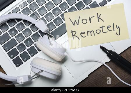 Work remotely. Memo stick on laptop keyboard with headset and pen ...