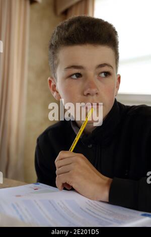 Boy chewing pencil in school classroom Stock Photo - Alamy