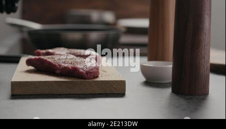 man grinding pepper on raw beef steak on oak board, wide photo Stock ...