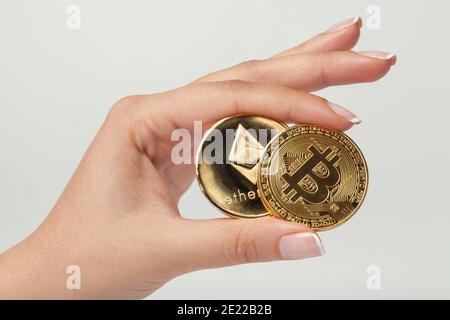 macro female hand holding bitcoin and ethereum side by side in front of ...