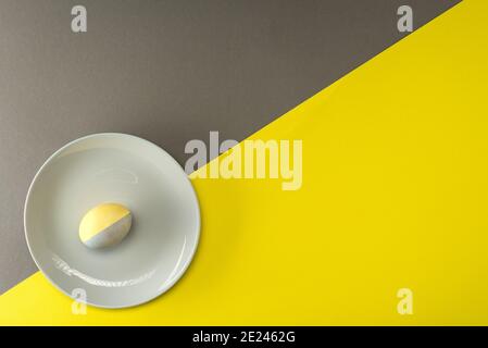Easter eggs painted yellow-gray in a gray plate on a yellow background ...