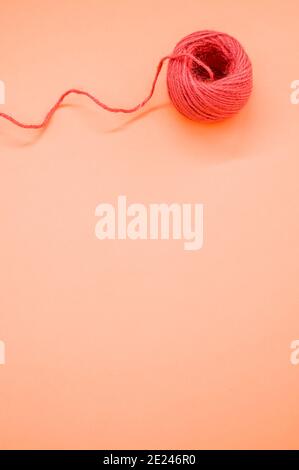 Vertical shot of bright red woolen yarn on a peach background Stock ...