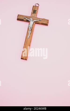 Vertical shot of a wooden crucifixion of Christ cross on a pink ...