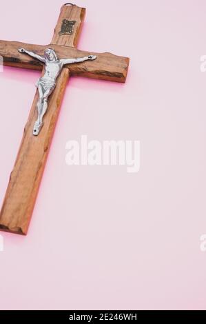 Vertical shot of a wooden crucifixion of Christ cross on a pastel peach ...
