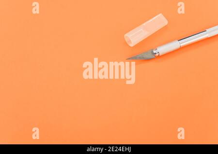 Top view of metallic scalpel with cap isolated on orange background ...