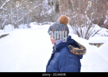 Retired woman with colorful jacket and hat in rural area with snow ...