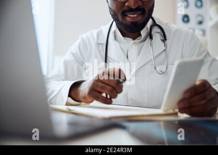 Smiling medical specialist using mobile phone over blue studio ...
