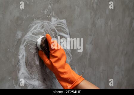 Professional cleaner wearing orange protective gloves sanitizing white ...