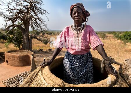 Old Batammariba woman standing in the granary on top of her takienta ...