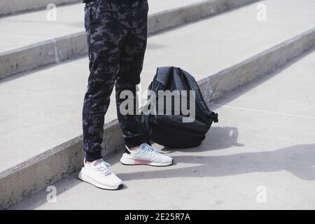 Backpack laying at a males feet outdoors Stock Photo - Alamy