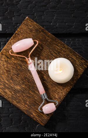 Massage roller for the face made of rose quartz with bottle of cosmetic ...