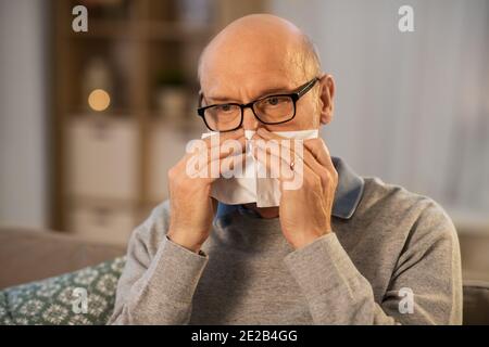 Sick bald senior man blowing his nose with tissue. having flu, corona ...