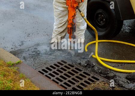 Jackhammer with a pneumatic drill perforating the asphalt of an urban ...