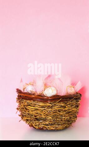 Easter composition with wicker nest and pink colored eggs on white ...