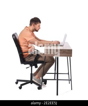 Man with poor posture using laptop while sitting on chair against beige ...
