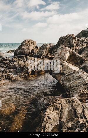 Wavy ocean hitting the rocks and gleaming under the blue sky Stock ...