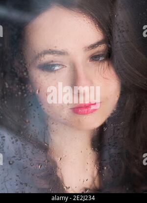 Portrait of a woman behind a wet glass Stock Photo - Alamy