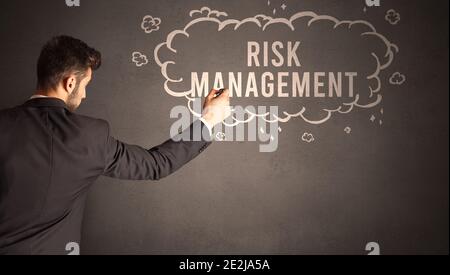 businessman drawing a cloud with RISK MANAGEMENT inscription inside ...