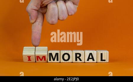 Moral or immoral symbol. Hand turns cubes and changes the word 'immoral ...