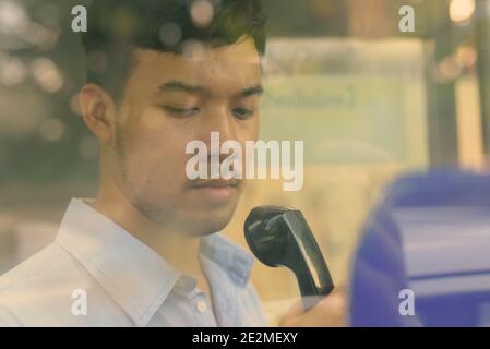 Young Asian businessman using the payphone outdoors Stock Photo - Alamy
