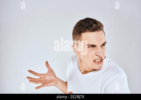 Emotional man gestures with his hands displeasure white t-shirt light ...