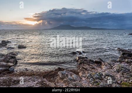 View across a turbulent sea at sunset towards Clare Island from Roonagh ...