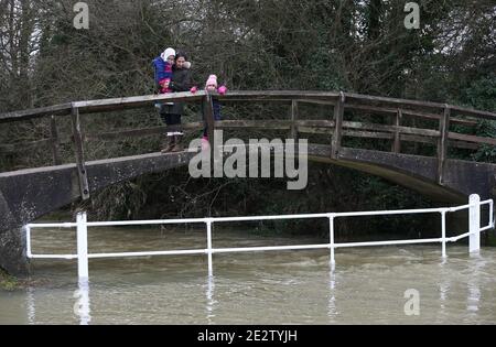People cross a bridge over a swollen River Chelmer in the village of ...