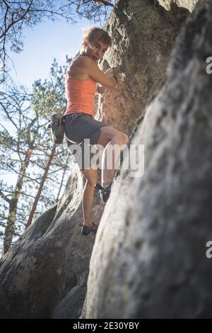 A female rock climber bouldering topless on the roof of a cave in ...
