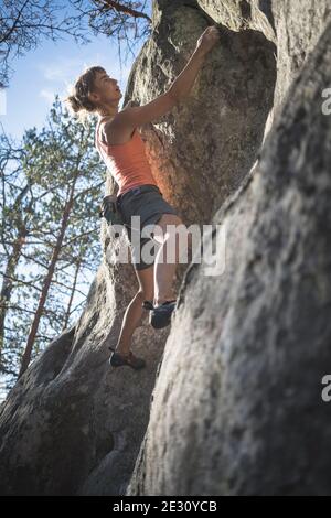 A female rock climber bouldering topless on the roof of a cave in ...