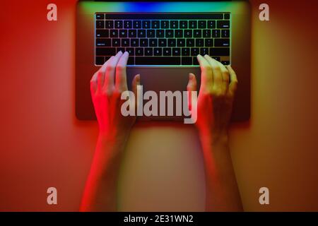Hands typing on modern backlit keyboard for digital technology work and ...