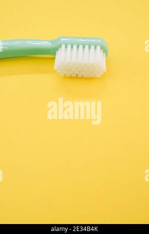 Vertical shot of turquoise toothbrush on a yellow surface for a copy ...