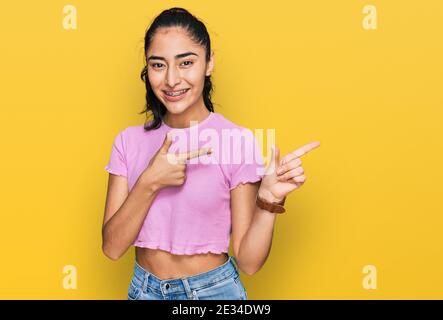 Teenager girl pointing her fingers to the side. Isolated background ...