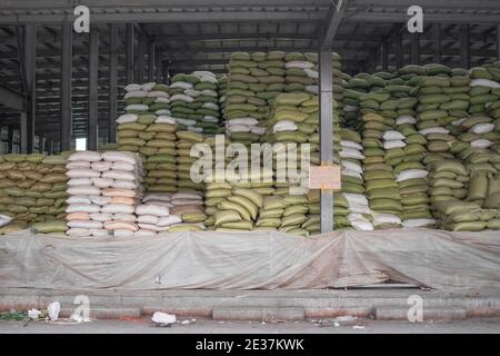 Green and white bags of rice stacked tall at a local storage warehouse ...