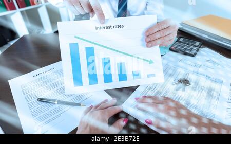 Estate agent showing the decrease of interest rates to his client ...