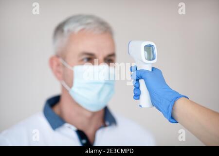 Doctor hand measuring mature man's temperature with digital thermometer ...