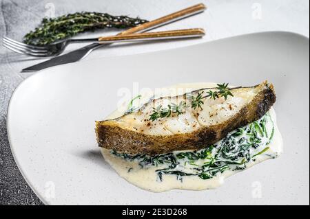Baked Halibut fish steak with spinach. White background. Top view. Copy ...