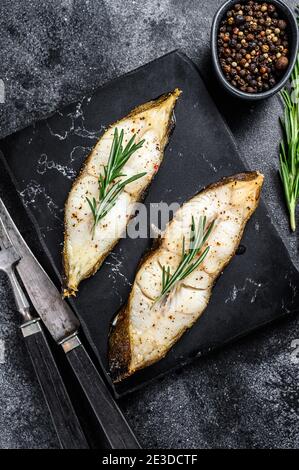 Halibut fish steak with rosemary. Black background. Top view. Copy ...