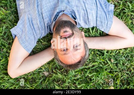 Adult caucasian man lying upside down portrait on grass Stock Photo - Alamy