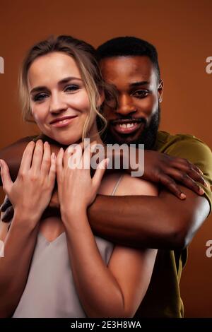oung pretty couple diverse races together posing sensitive on brown ...