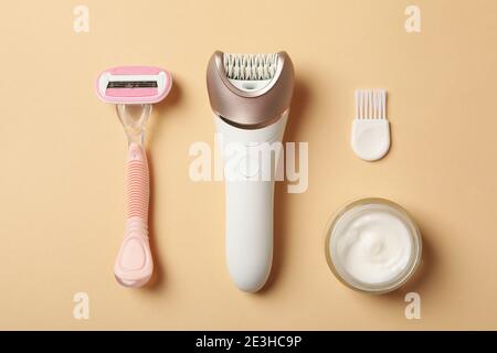 Epilator, razor and cream on beige background Stock Photo - Alamy