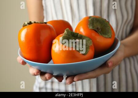 Healthy woman eating persimmon kaki fruit at home. Close up from above ...