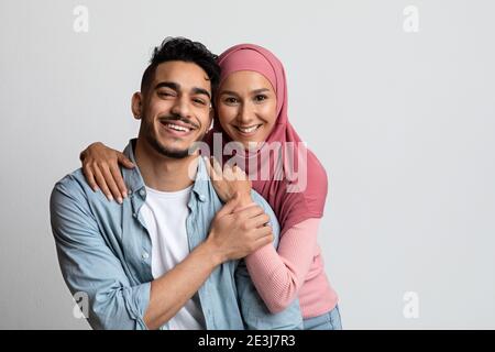 Portrait of romantic smiling muslim couple sitting on beige studio ...