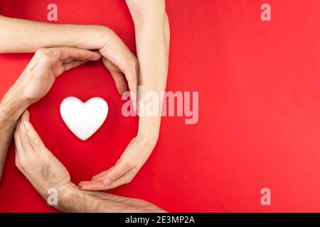 Hands of parents and a child surround a white heart on a blue ...