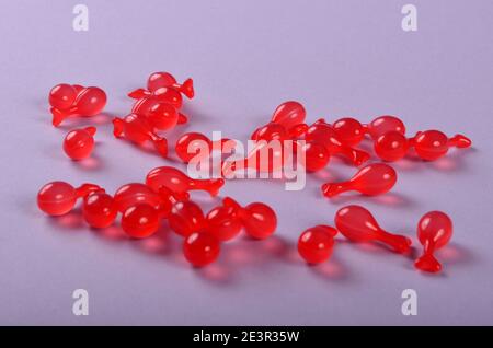 Pharmaceutical soft red gelatin capsules on violet background ...