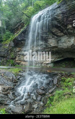 A roadside waterfall going over a cliff and over a road that is now ...