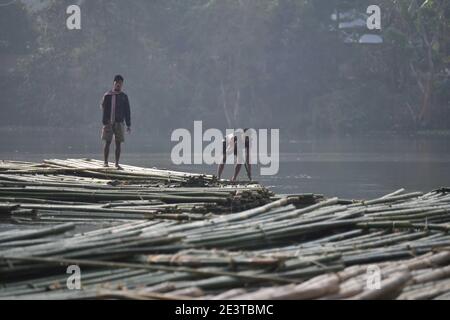 Laborers collect heaps of bamboo on a river to be sold at a floating ...