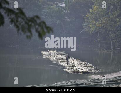 Laborers collect heaps of bamboo on a river to be sold at a floating ...